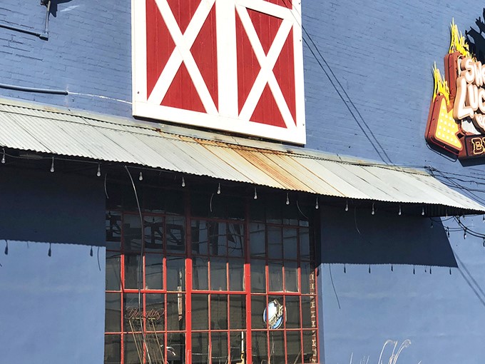 The blue exterior with its red barn door isn't trying to impress anyone—until you smell what's happening inside. BBQ paradise awaits.