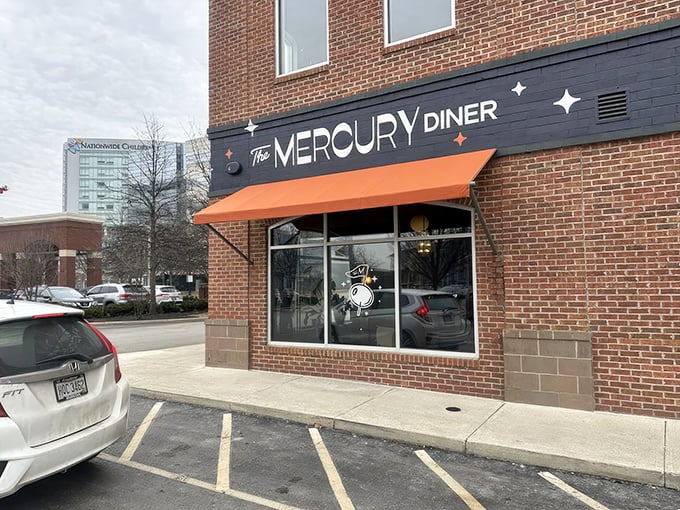 The retro-futuristic facade of The Mercury Diner makes a bold statement with its navy blue paint, orange awning, and playful star accents—cosmic comfort food awaits inside.