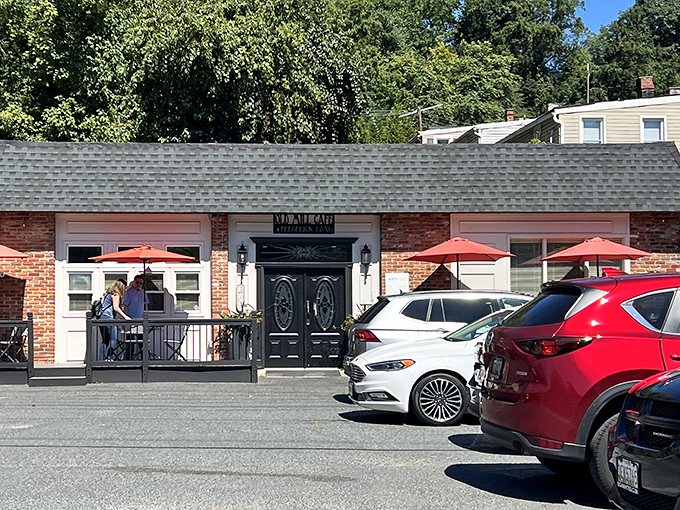 The unassuming brick exterior of Old Mill Cafe beckons with its elegant black doors and cheerful red umbrellas—like a secret breakfast society waiting to initiate you.