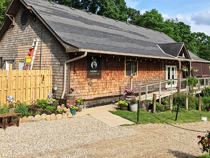 The rustic cedar-shingled exterior of Ugly Bunny Winery welcomes visitors with colorful flower gardens and a gravel path that whispers, "Slow down, you've arrived."