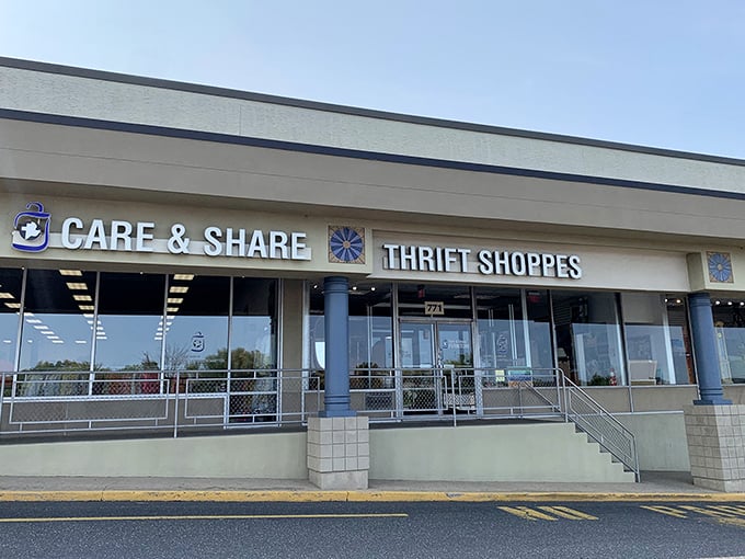 The exterior of Care & Share Thrift Shoppes stands proudly amid landscaped grounds, where bargain hunters' dreams bloom as vibrantly as those flowering trees.