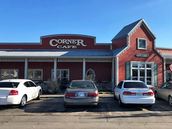 The red barn-like exterior of Corner Cafe stands proudly against the Missouri sky, complete with patriotic bunting and a welcoming porch that practically whispers, "Come on in, hungry traveler."
