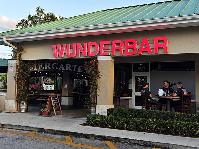 The green-roofed oasis of Wunderbar beckons with its vibrant red signage and lush entrance – a little slice of Bavaria hiding in plain sight.