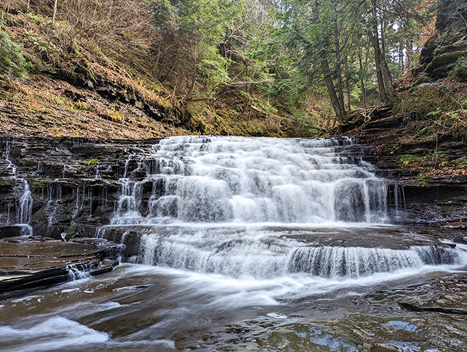 Nature's tiered masterpiece cascades over ancient rock formations, creating a swimming hole that makes you wonder why you ever bothered with chlorinated pools.