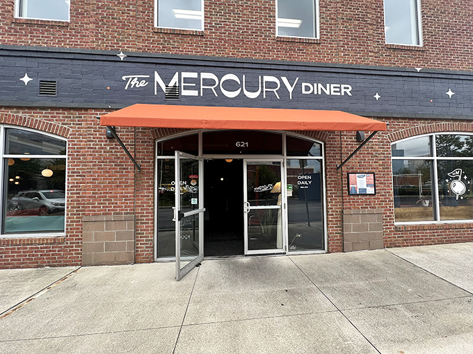 The retro-futuristic facade of The Mercury Diner makes a bold statement with its navy blue paint, orange awning, and playful star accents—cosmic comfort food awaits inside.