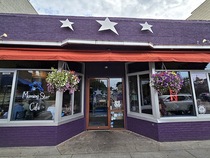 The purple facade with its cheerful red awning and hanging flower baskets isn't just eye-catching—it's nature's way of saying "breakfast is served!"
