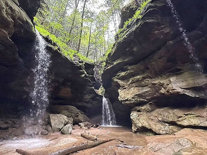 Nature's amphitheater puts on quite a show here, with twin waterfalls cascading down moss-covered cliffs while sunlight filters through the canopy above.