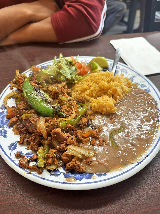 The adobada plate arrives like a color wheel of Mexican flavors—spiced meat, golden rice, and creamy beans creating a harmony that makes taste buds sing.