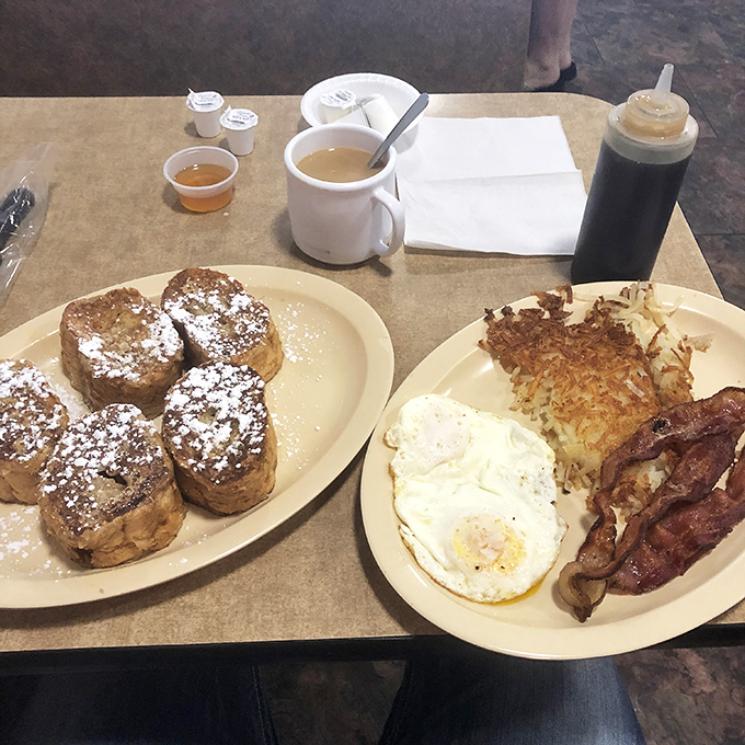 French toast dusted with powdered sugar alongside eggs and bacon—the breakfast trinity that makes getting out of bed worthwhile.