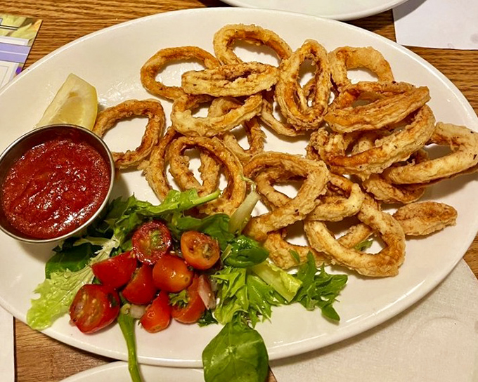 Calamari rings fried to golden perfection—crunchy on the outside, tender within. The marinara sauce stands by, ready for its dipping debut.