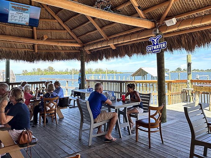 The thatched-roof deck offers panoramic water views where strangers become friends over platters of fresh catch and stories that grow taller with each drink.