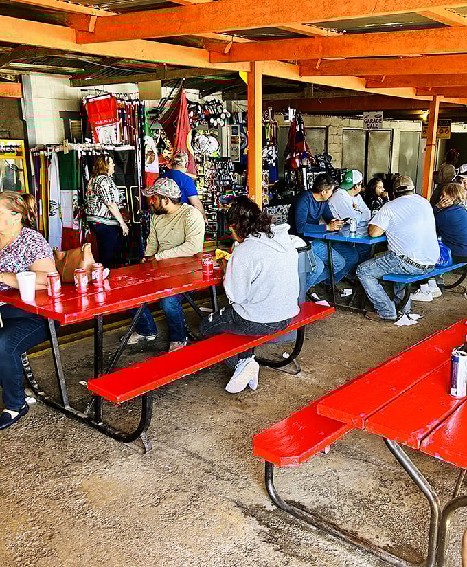 The social heart of the market—red picnic tables where strangers become friends over cold drinks and flea market finds.
