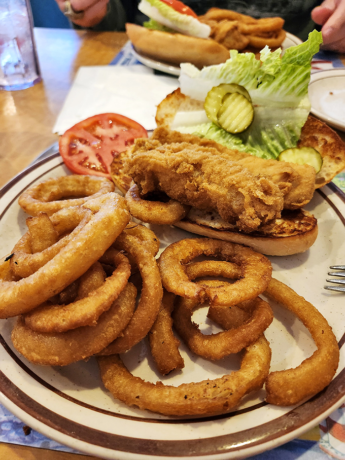 A chicken sandwich surrounded by an army of onion rings. This isn't just lunch – it's a fortress of fried goodness that demands your full attention.