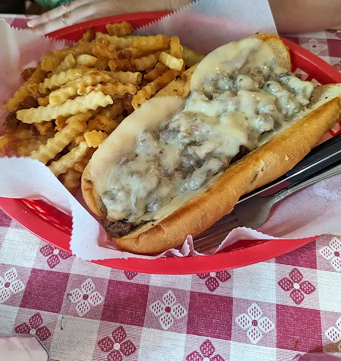 A Philly cheesesteak that would make Philadelphians nod in respect, served with a generous pile of crinkle-cut fries that refuse to be ignored.