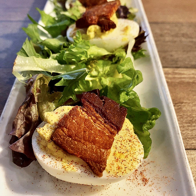 Deviled eggs living their best life with crispy pork belly on top. These aren't your church picnic appetizers—they've gone to finishing school.