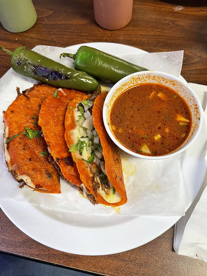 Crispy-edged, cheese-crusted quesobirria tacos with consommé for dipping—the kind of dish that makes you want to hug whoever invented it.