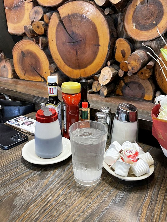 The wood cross-section wall creates a rustic backdrop for table essentials – like dining in a cozy cabin where breakfast is always the main event.