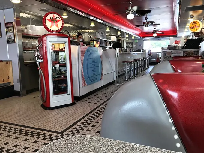 The counter view reveals the diner's heart—a vintage gas pump display, chrome finishes, and the promise of meals made with equal parts nostalgia and care. 