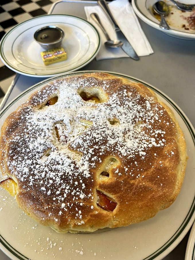 This pancake isn't just breakfast—it's dessert in disguise, with fruit peeking through like hidden treasures under a dusting of powdered sugar.