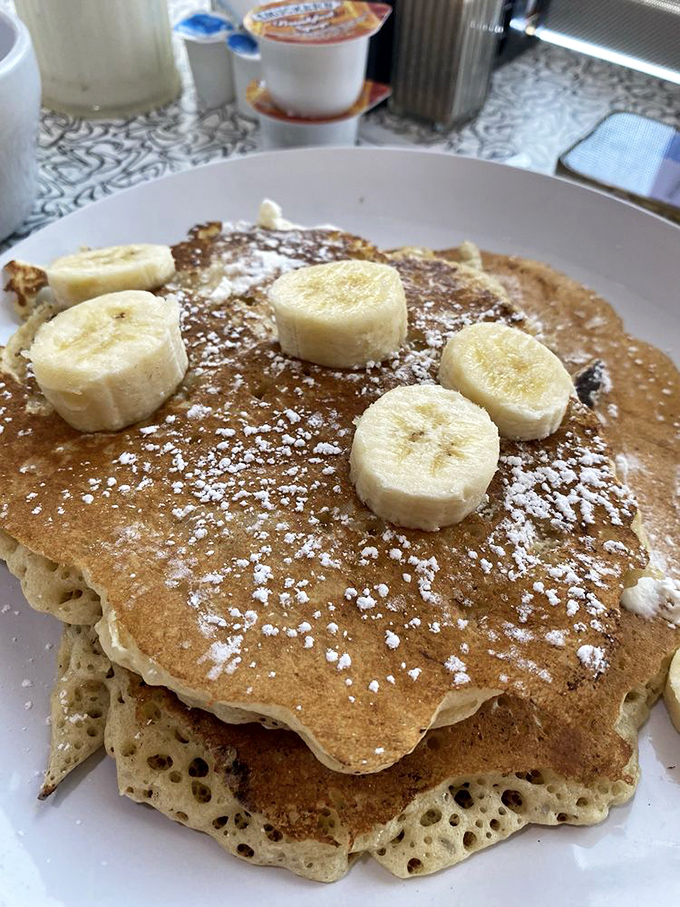 Pancakes so fluffy they could double as pillows, topped with banana slices and powdered sugar—breakfast or dessert? Why choose?