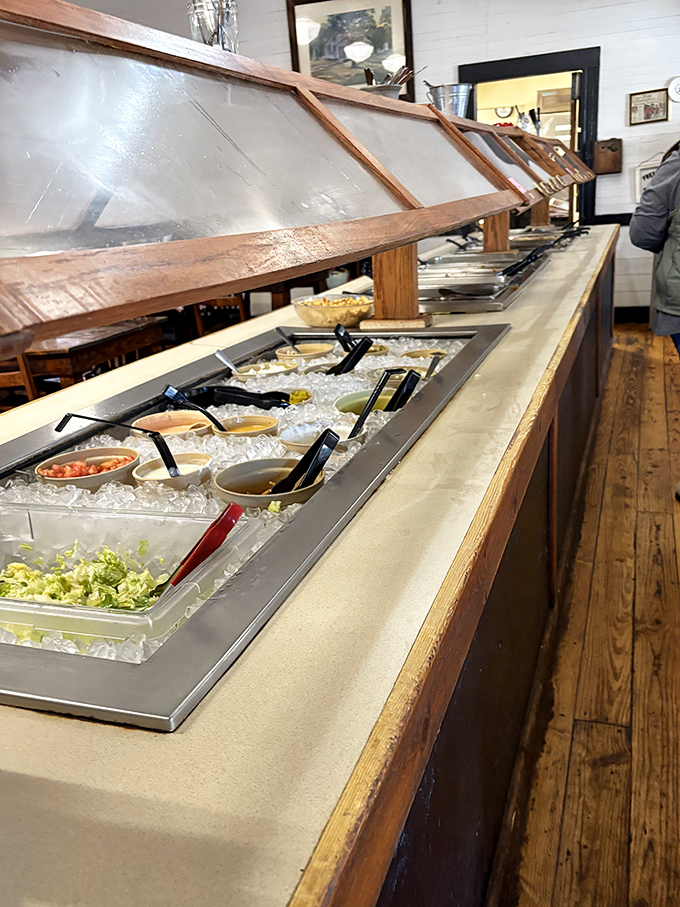 The salad bar isn't trying to be fancy, and that's precisely its charm—fresh ingredients waiting patiently under glass like treasures in a country museum.