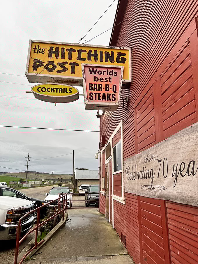 The Hitching Post's vintage signs whisper tales of decades spent perfecting smoky meat magic. 
