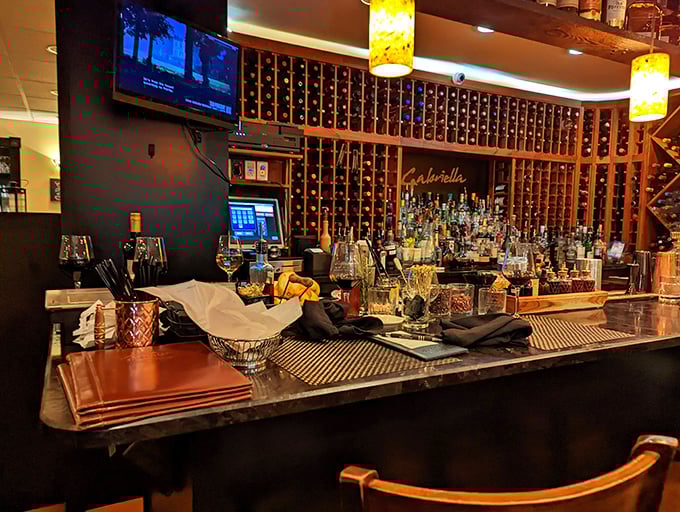 Behind that bar lies liquid happiness in bottles, where wine racks stretch toward the ceiling like a monument to good times.