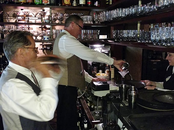 The art of the cocktail isn't lost here—white-jacketed bartenders still practice the sacred rituals of proper drink preparation.