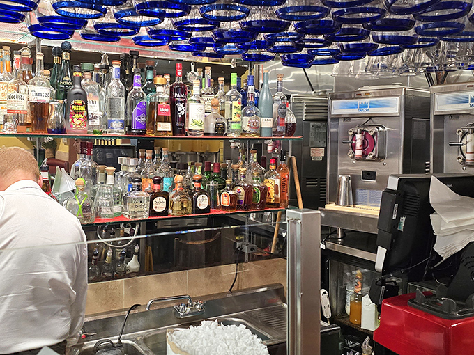 Behind the bar, an impressive array of spirits stands ready for transformation into signature cocktails. Those cobalt blue accents add a distinctive touch to the space.
