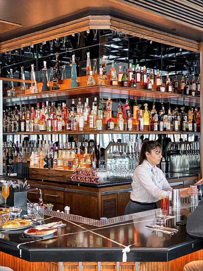 A bartender crafts drinks beneath what might be the most impressive spirits collection ever to grace a diner—this ain't your grandpa's coffee counter.