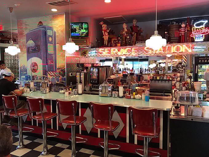 The counter seats—where solo diners become part of the show, watching short-order magic happen beneath the glow of "SERVICE STATION" neon.