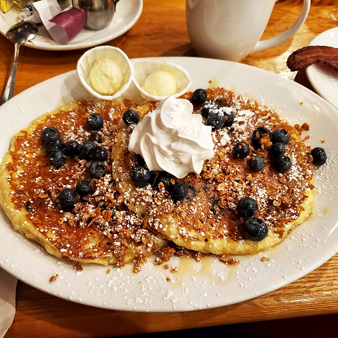 These blueberry pancakes aren't just topped with fruit—they're studded with bursts of berry joy like edible sapphires in a golden crown.