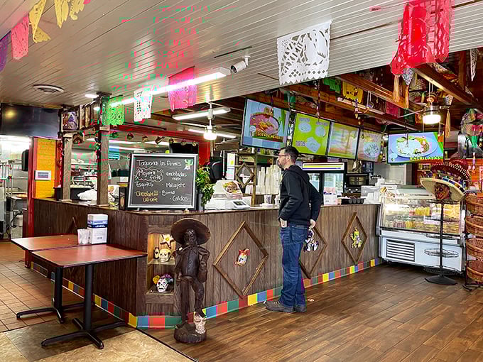The beating heart of Taqueria Los Primos, where culinary magic happens behind the counter while papel picado flutters overhead.