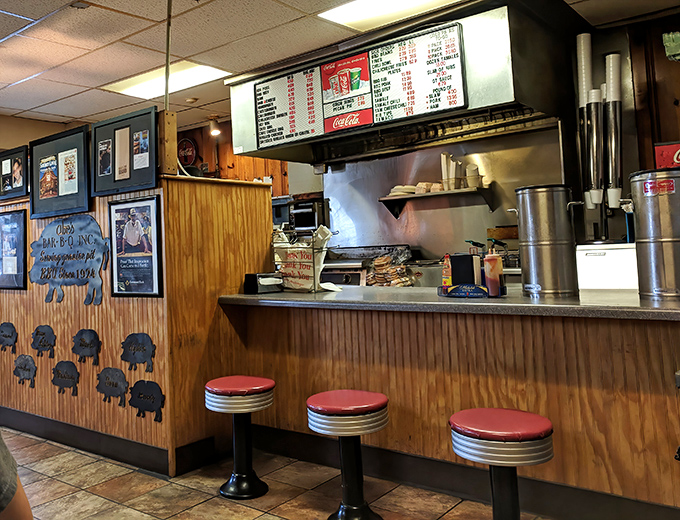 The counter where magic happens—red stools awaiting regulars, menu board overhead, and the promise of satisfaction just moments away.
