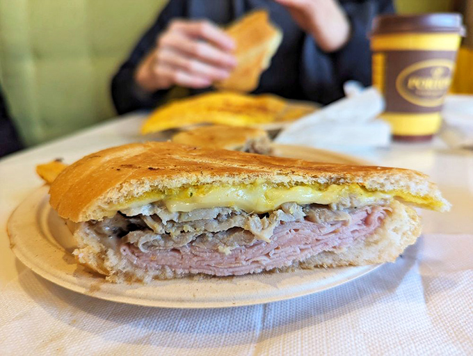 The Cuban sandwich, sliced to reveal its perfect stratification of meats and cheese—a cross-section of happiness between two pieces of bread.
