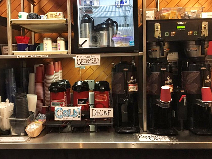 The coffee station—where morning dreams are brewed and second chances at humanity are dispensed with free refills for dine-in customers.