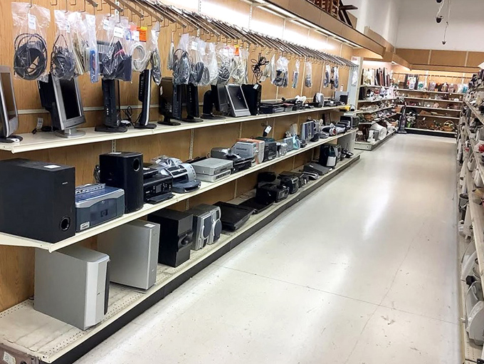 Electronic archaeology at its finest – each shelf a time capsule of technological evolution from boomboxes to DVD players.