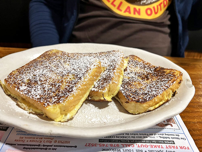 French toast that's crossed the line from breakfast to dessert – powdered sugar, golden exterior, and a custard-like center that defies gravity.