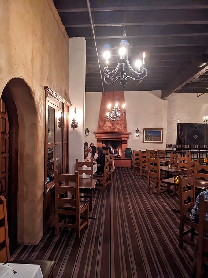 Pull up a chair and step back in time—this cozy dining room feels like a warm hug from an old adobe inn, complete with flickering sconces and a fireplace ready for stories.
