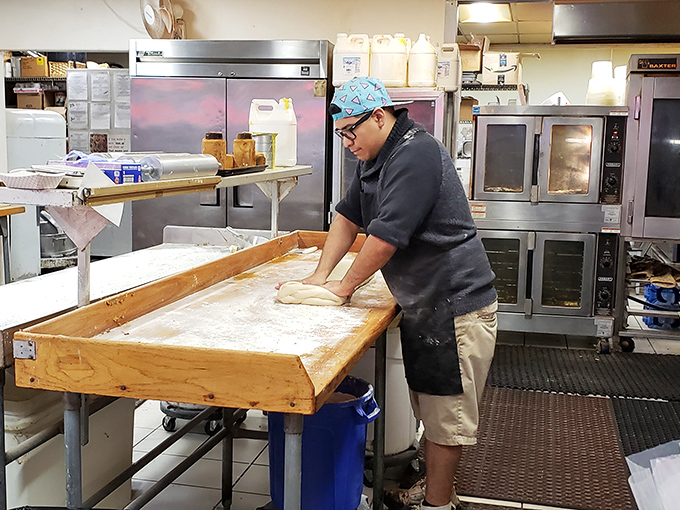 The baker's hands tell stories of thousands of perfect rolls. This is where the magic happens, one stretch of dough at a time.
