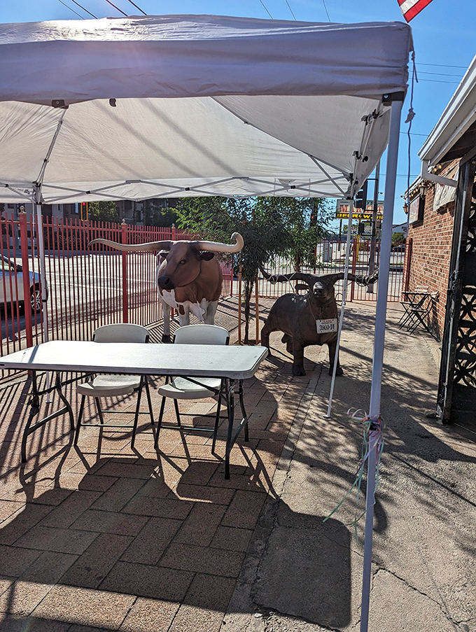 Outdoor seating guarded by metal livestock sentinels—because nothing says "authentic Texas" quite like dining under the watchful eyes of iron longhorns.