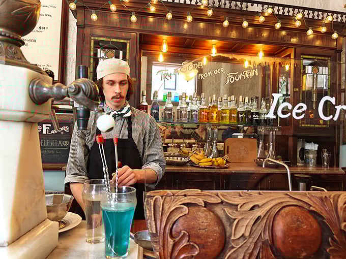 The soda jerk's bow tie and paper hat aren't costumes—they're symbols of dedication to craft. That blue concoction might just change your life.