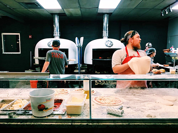 Pizza artisans at work, transforming simple dough into edible art. Those aren't just ovens—they're portals to flavor country, burning hot enough to cook a pizza in 90 seconds.