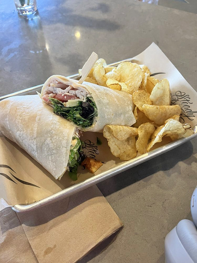 This wrap doesn't just hold ingredients—it embraces them in a tortilla hug alongside chips that clearly know they're the supporting actors.