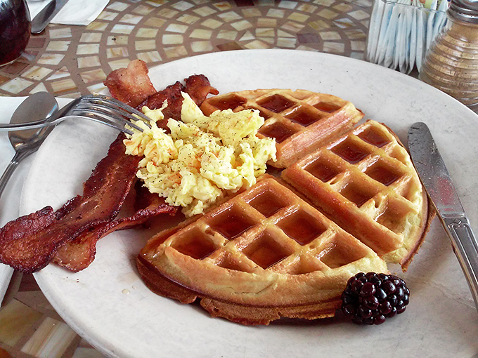 A golden waffle with eggs and bacon—the holy trinity of breakfast. That blackberry isn't just fruit; it's nature's perfect punctuation mark.