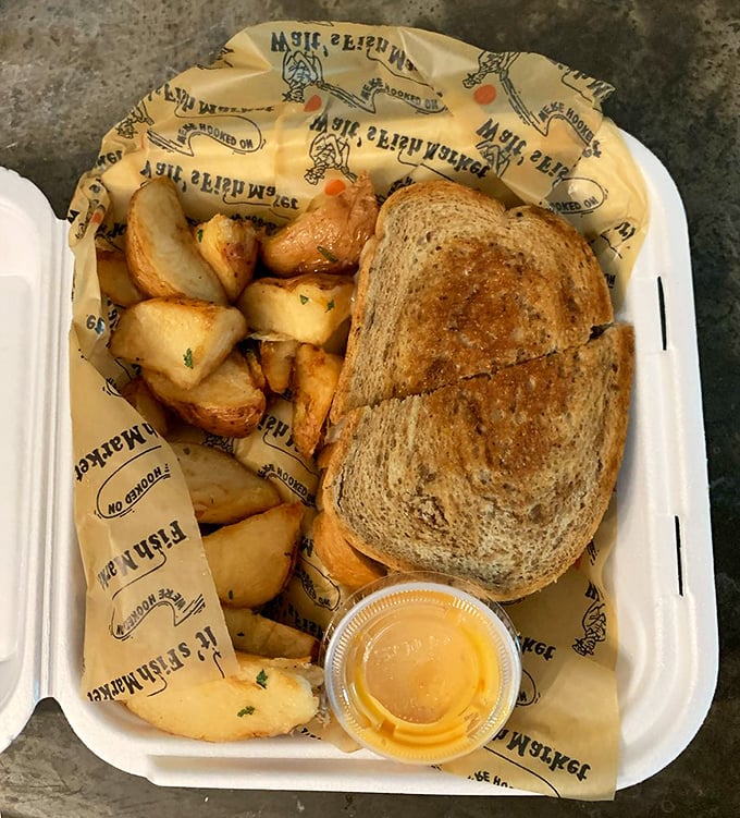 The sandwich and potatoes arrive on branded paper – a meal that speaks of tradition, simplicity, and flavors that don't need fancy china to impress.