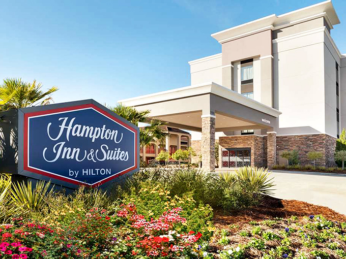 The Hampton Inn's landscaped entrance offers weary travelers a comfortable respite without Manhattan prices – proving affordable comfort isn't an oxymoron.