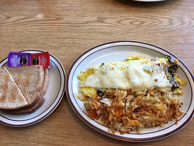 An omelet so perfectly executed it could make a French chef reconsider their life choices, served with hash browns that actually taste like potatoes.