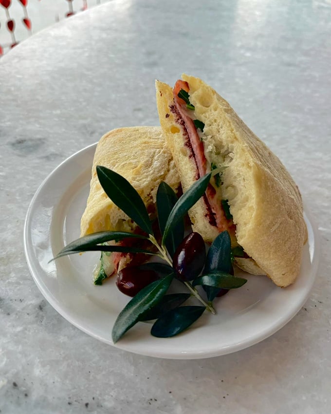 A sandwich garnished with olive branches—either a peace offering to your hunger or a Mediterranean wink to its Greek-inspired roots.