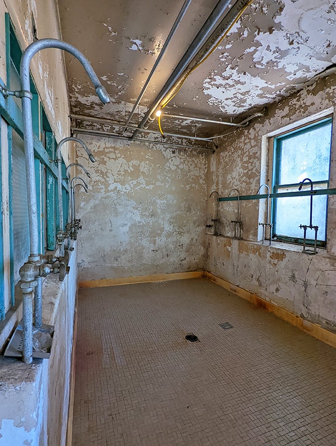The institutional shower room, with its utilitarian tile floor and exposed plumbing, speaks volumes about the spartan conditions that were once considered progressive reform.
